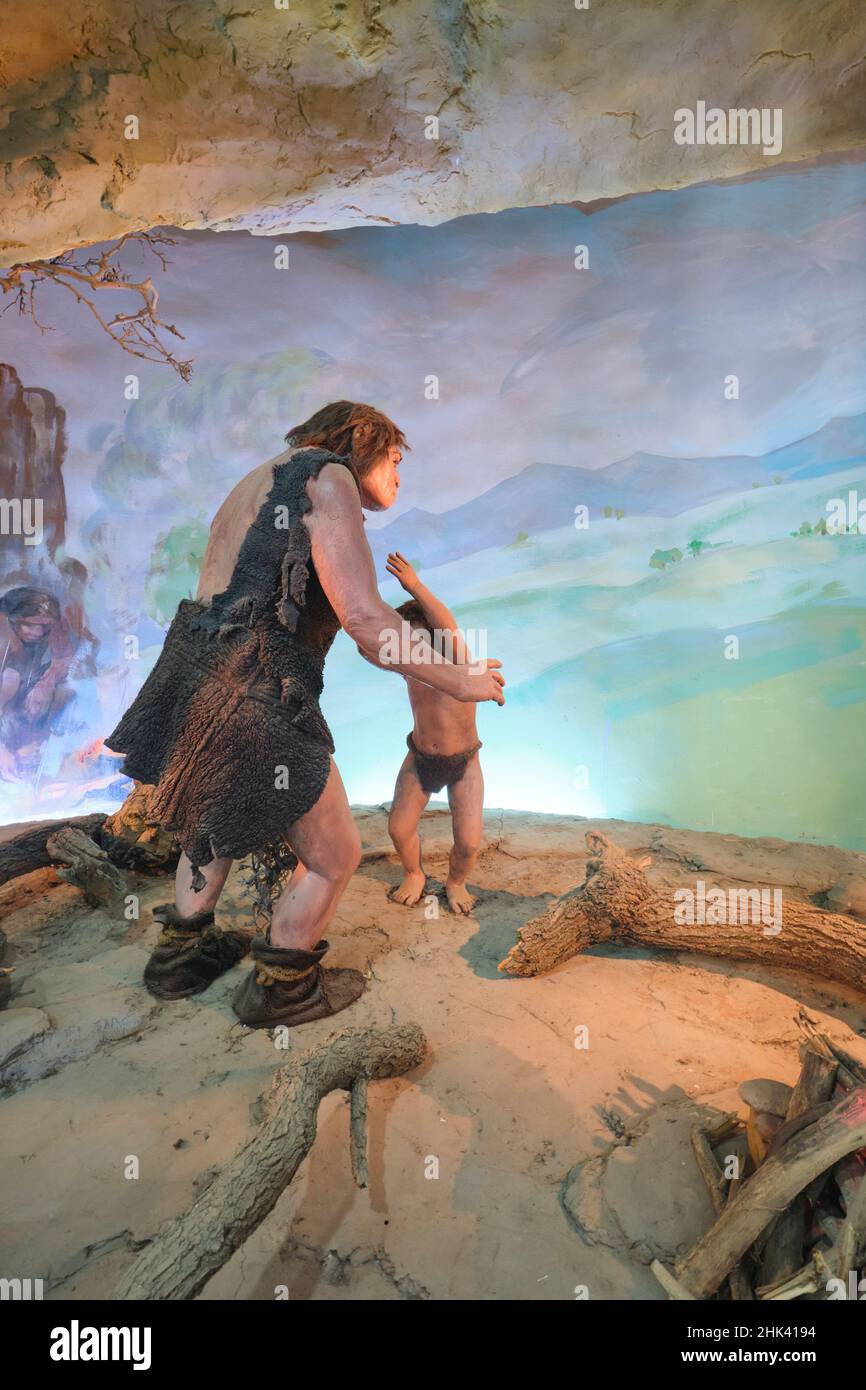A large diorama featuring people from the stone age. Father and child ...