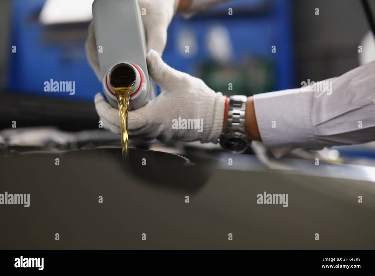 Master repairman pouring engine oil under hood of car closeup Stock ...