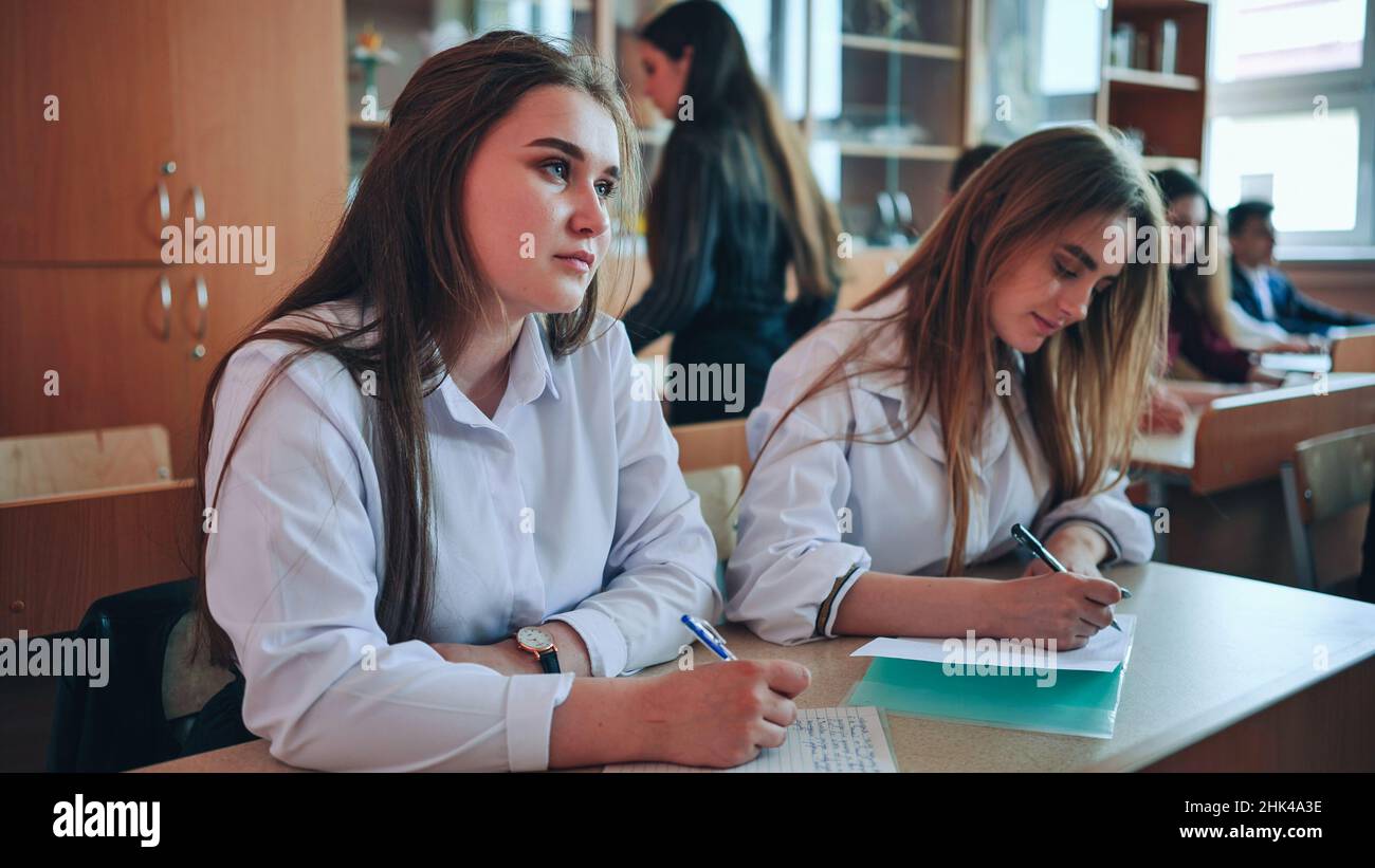 Pupils of the 11th grade in the class at the desks during the lesson ...