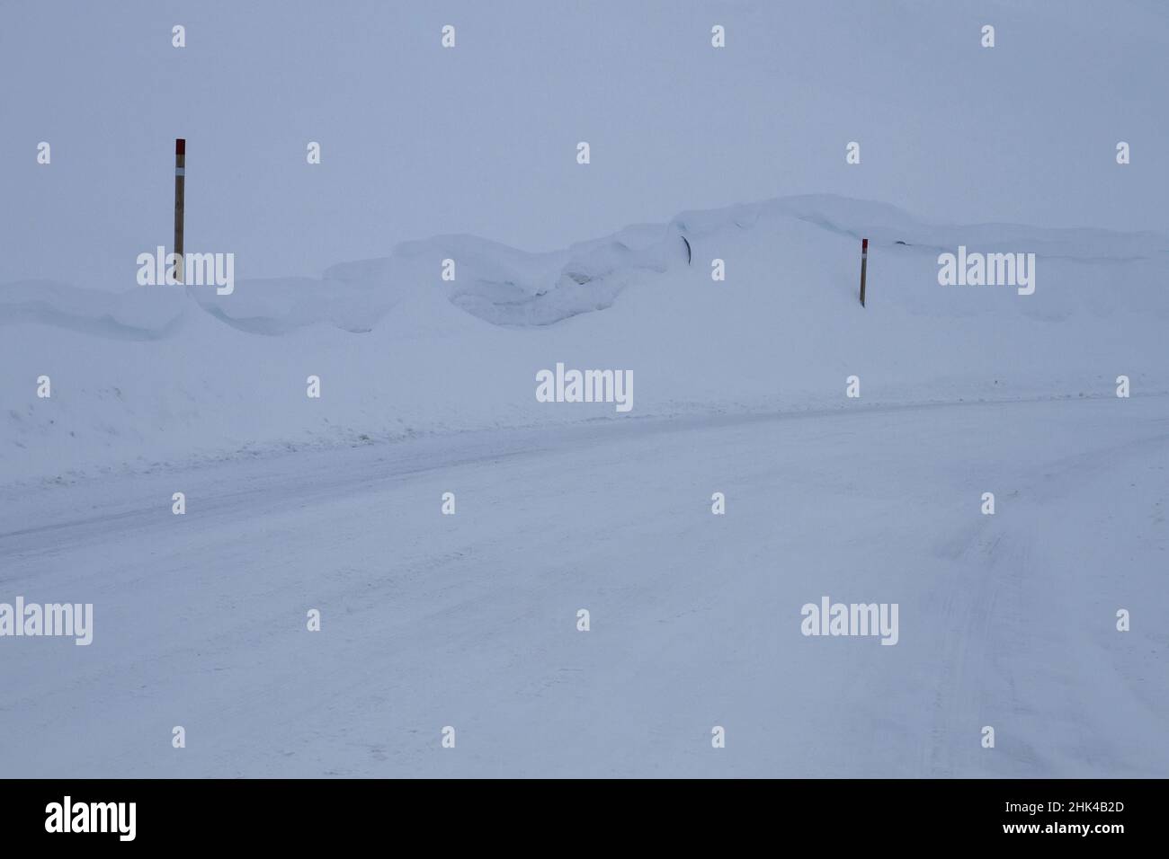 Frosty slippery mountain road with traffic signs buried by the snow ...