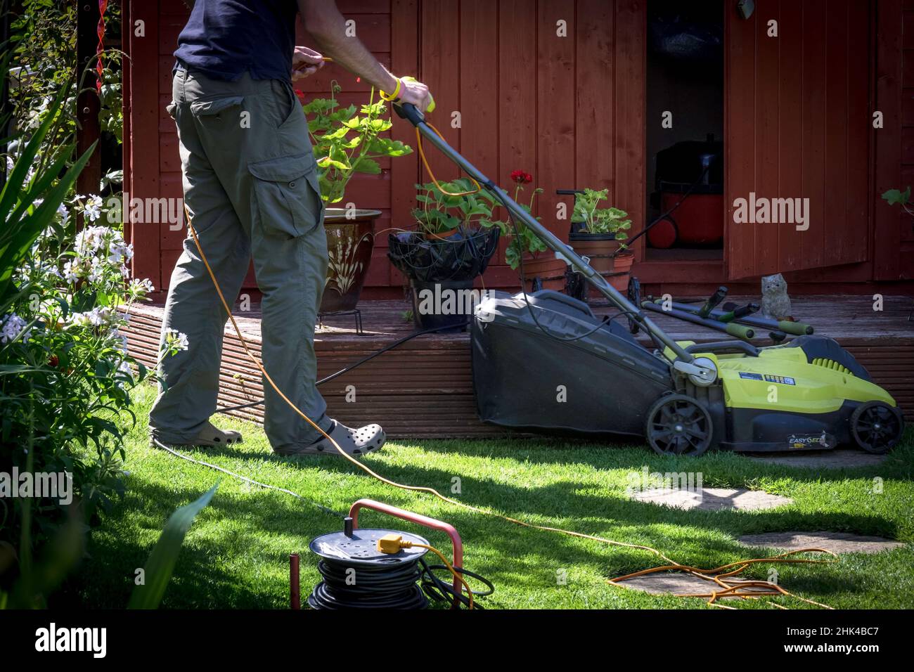 Man mowing a lawn in the grounds of garden home Stock Photo - Alamy