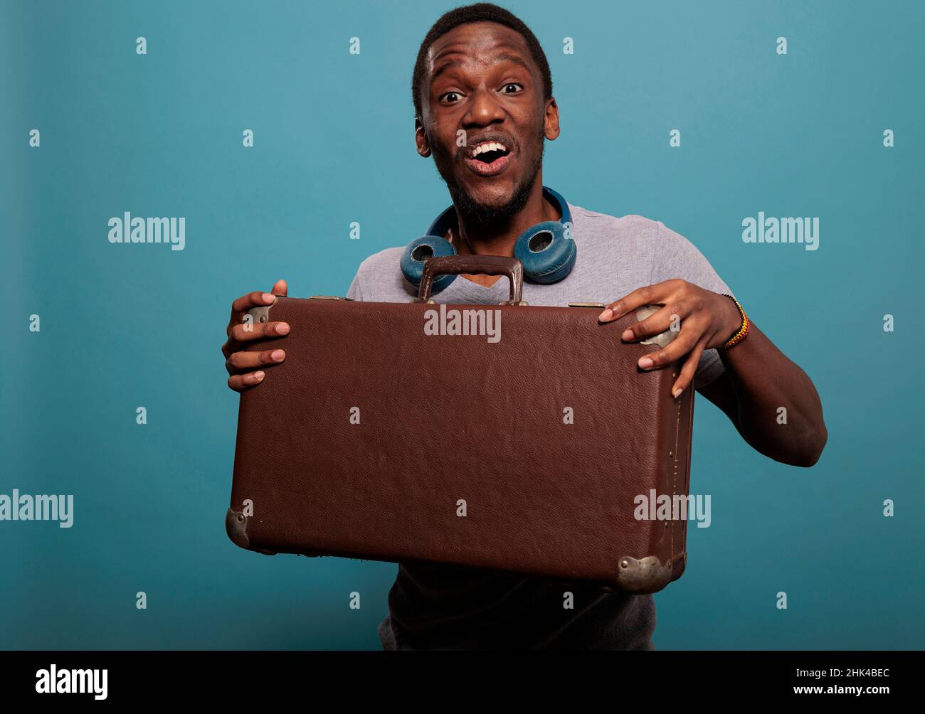 Joyful person carrying briefcase luggage to leave on vacation, wearing ...