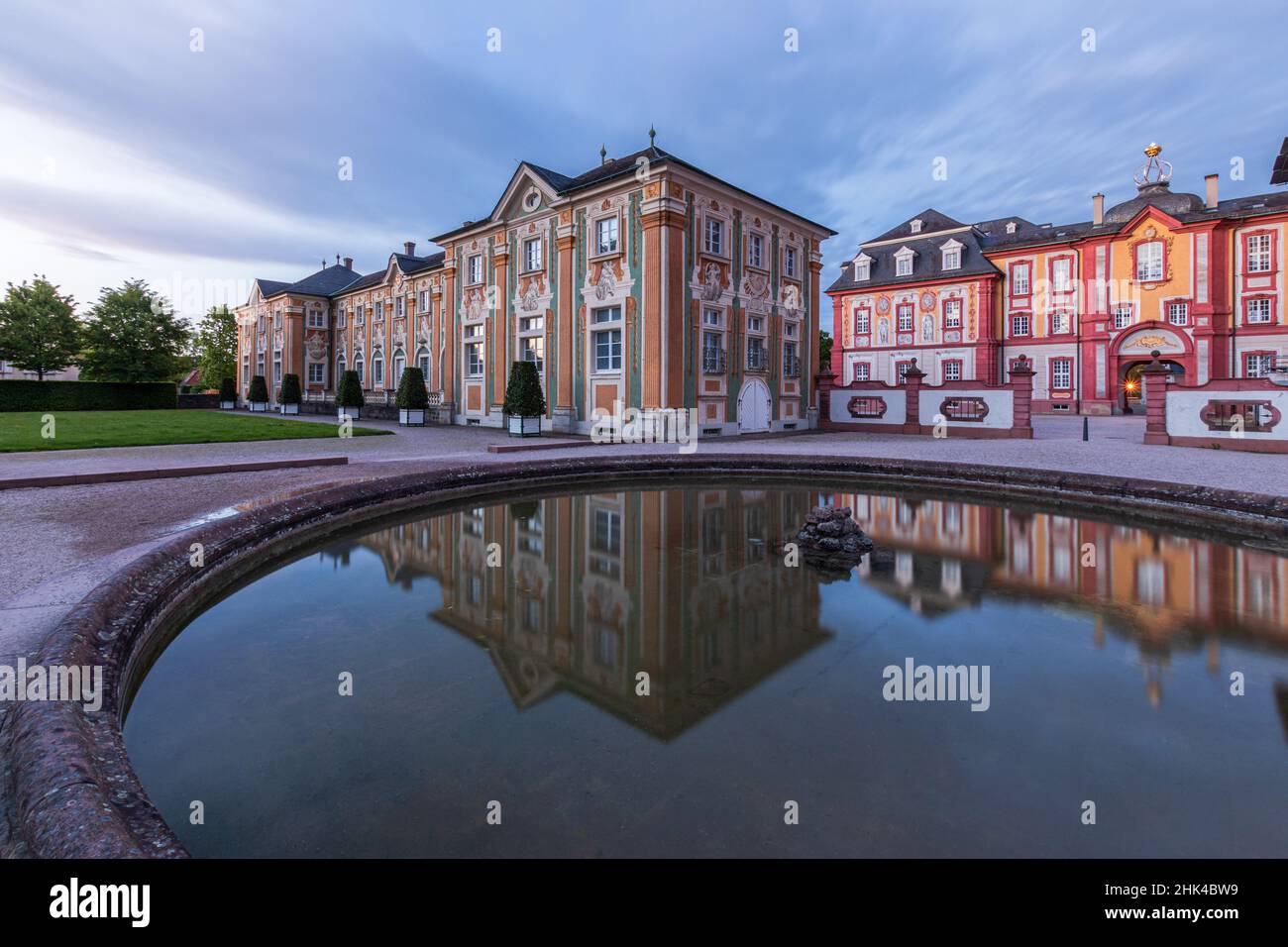 Bruchsal castle at blue hour with a fountain in the foreground and ...
