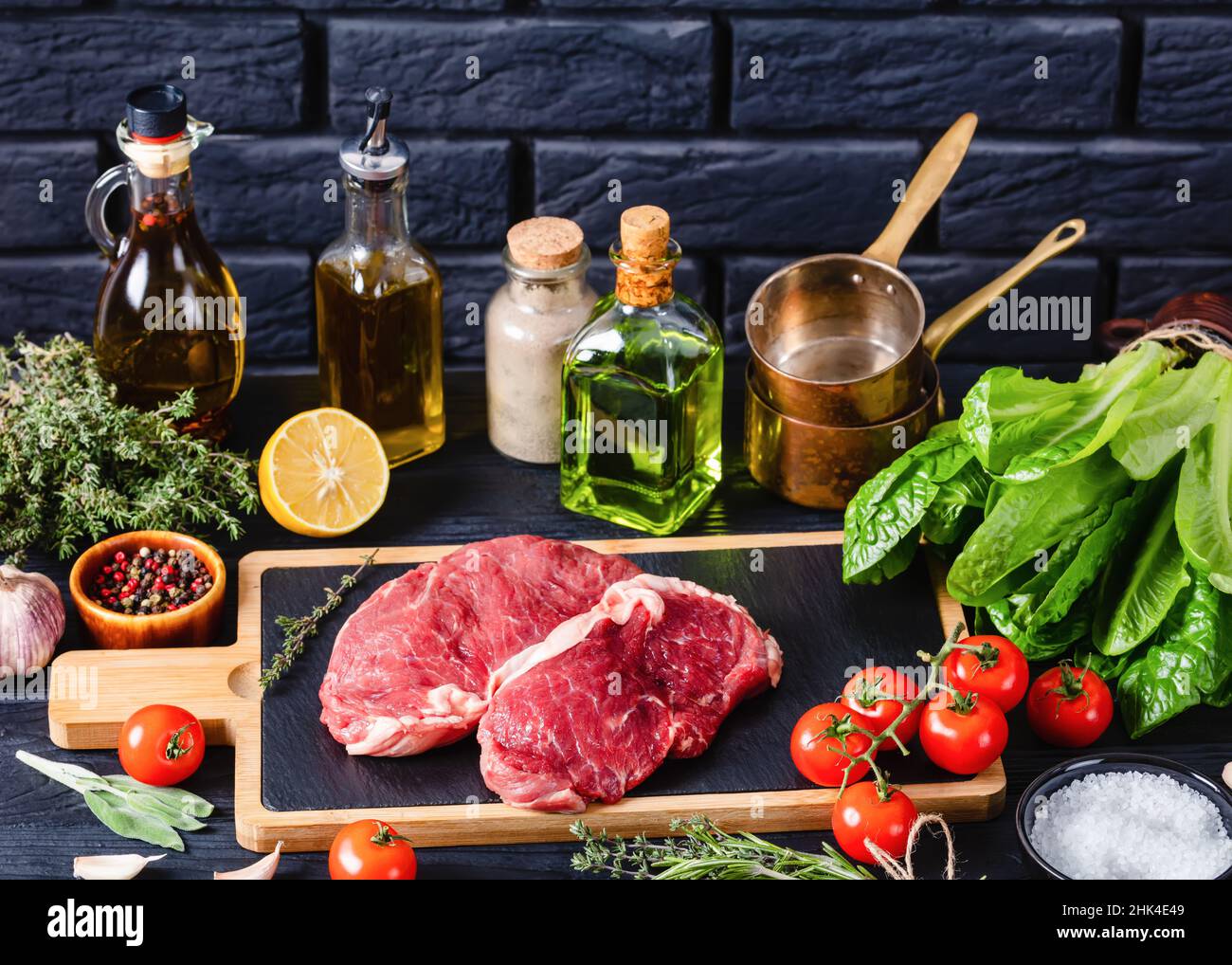 raw striploin steaks on a wood board on a kitchen table with ...