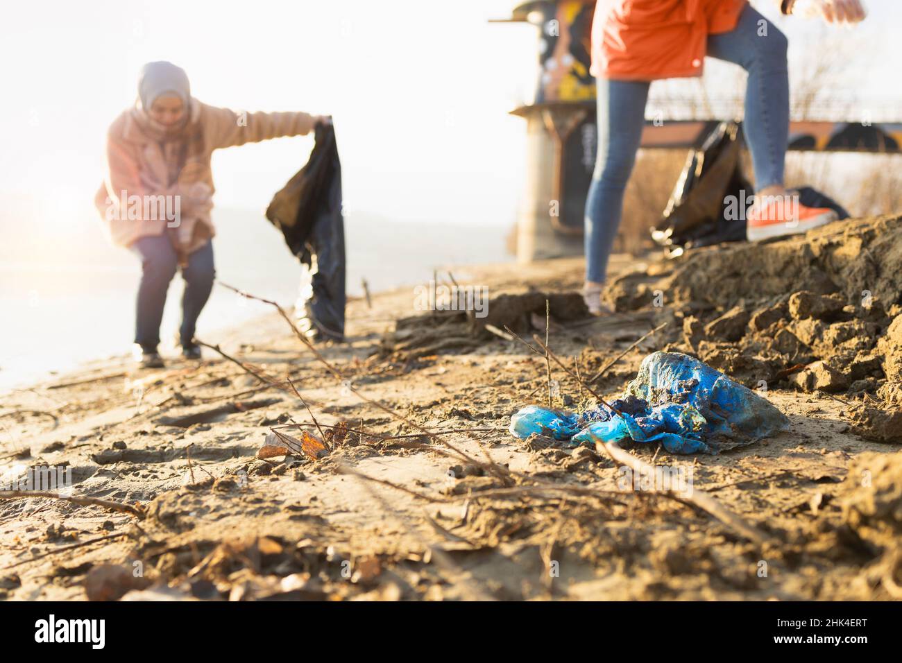 Two young volunteers cleaning up plastic bags from a beach Stock Photo ...