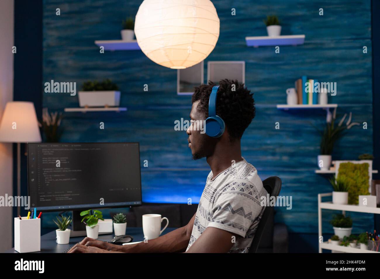 Programmer man wearing headphones typing binary code for website security working remote frrom ...