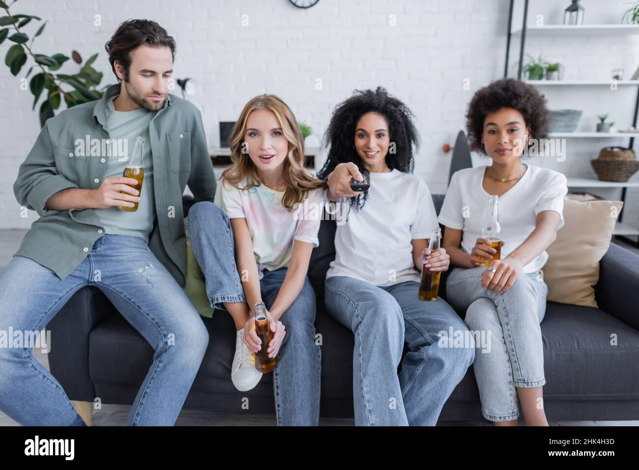 cheerful african american woman clicking channels near friends sitting ...