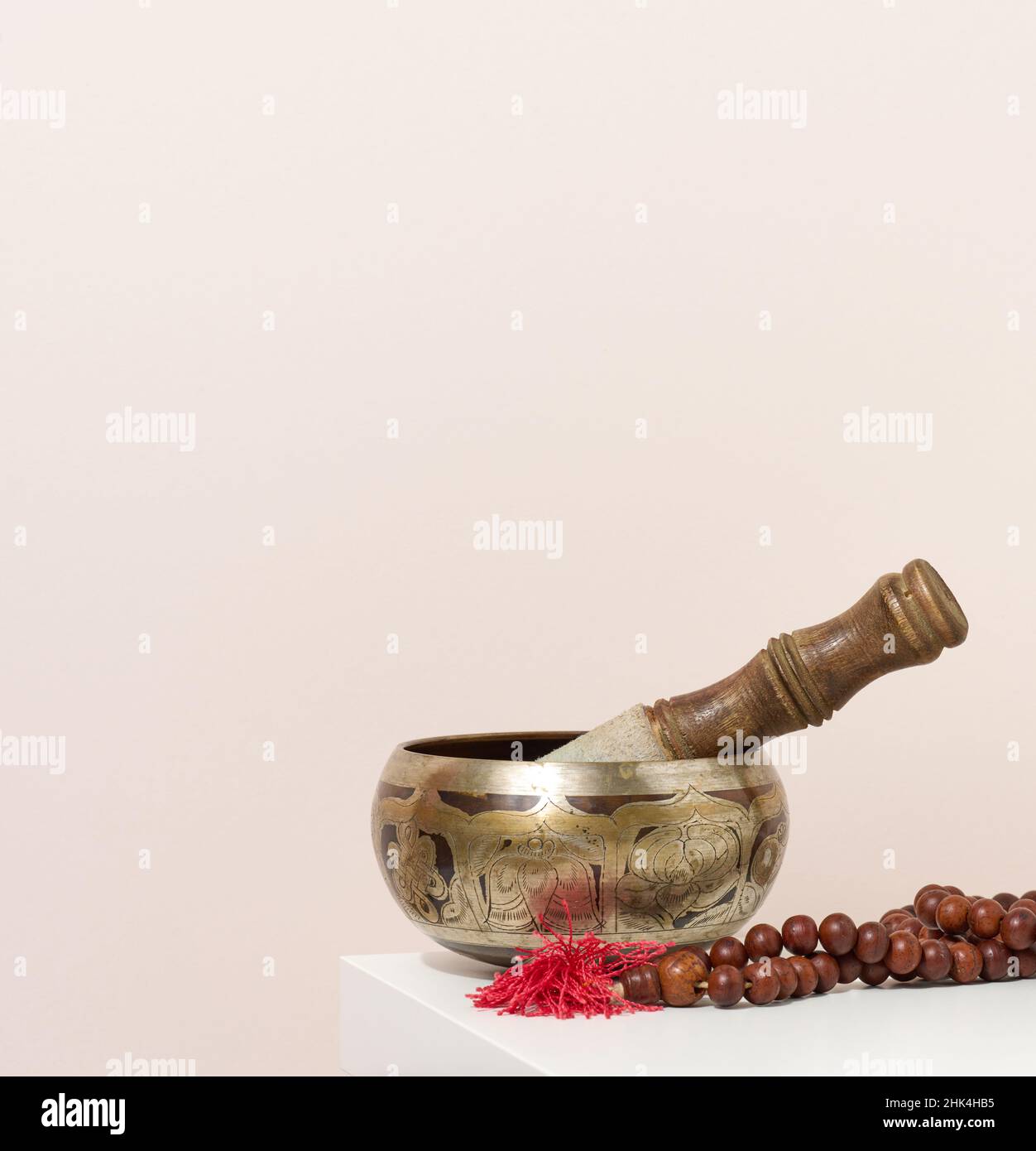 copper singing bowl and wooden clapper on a white table. Musical ...