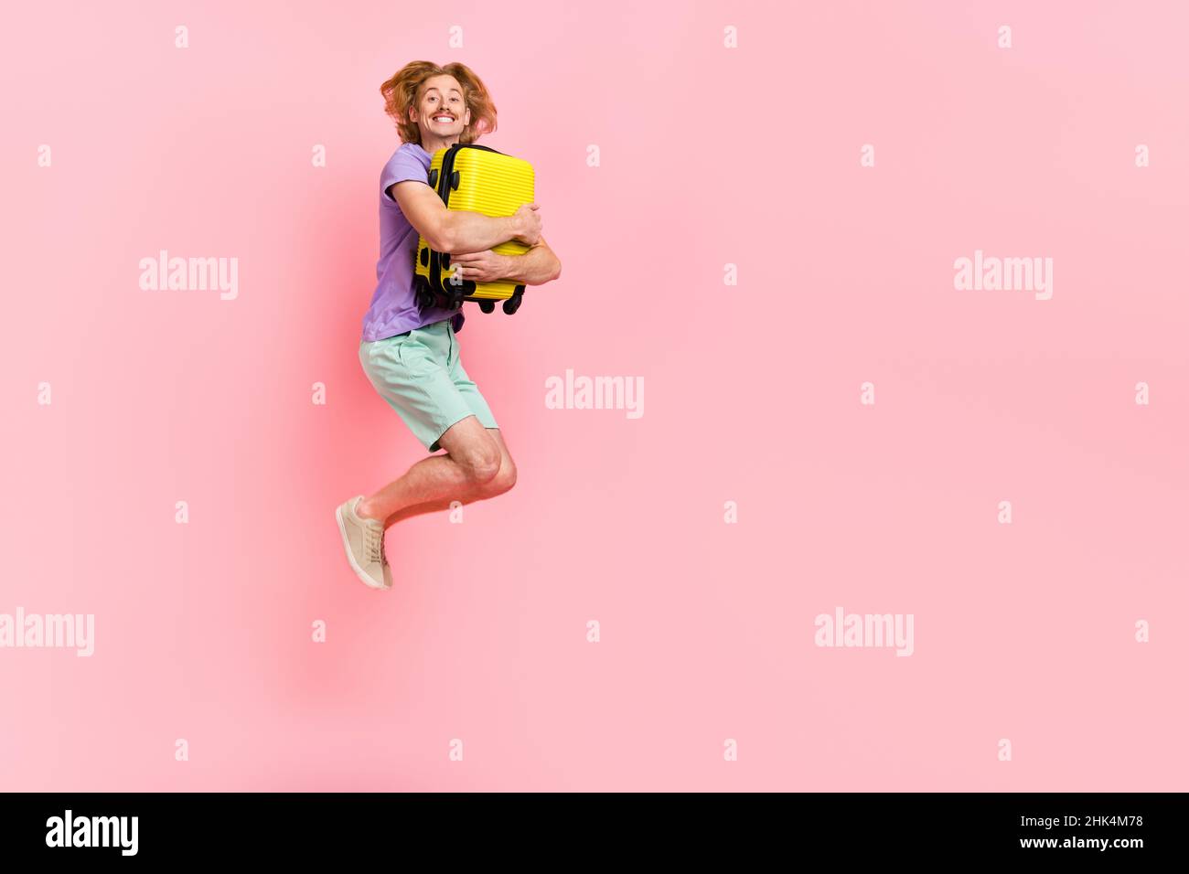 Full length body size view of attractive cheery guy jumping hugging bag ...