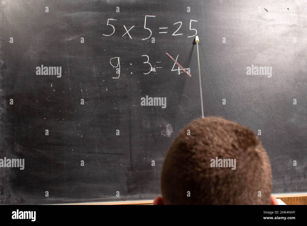 Boy shows arithmetic problems with stick on blackboard Stock Photo - Alamy