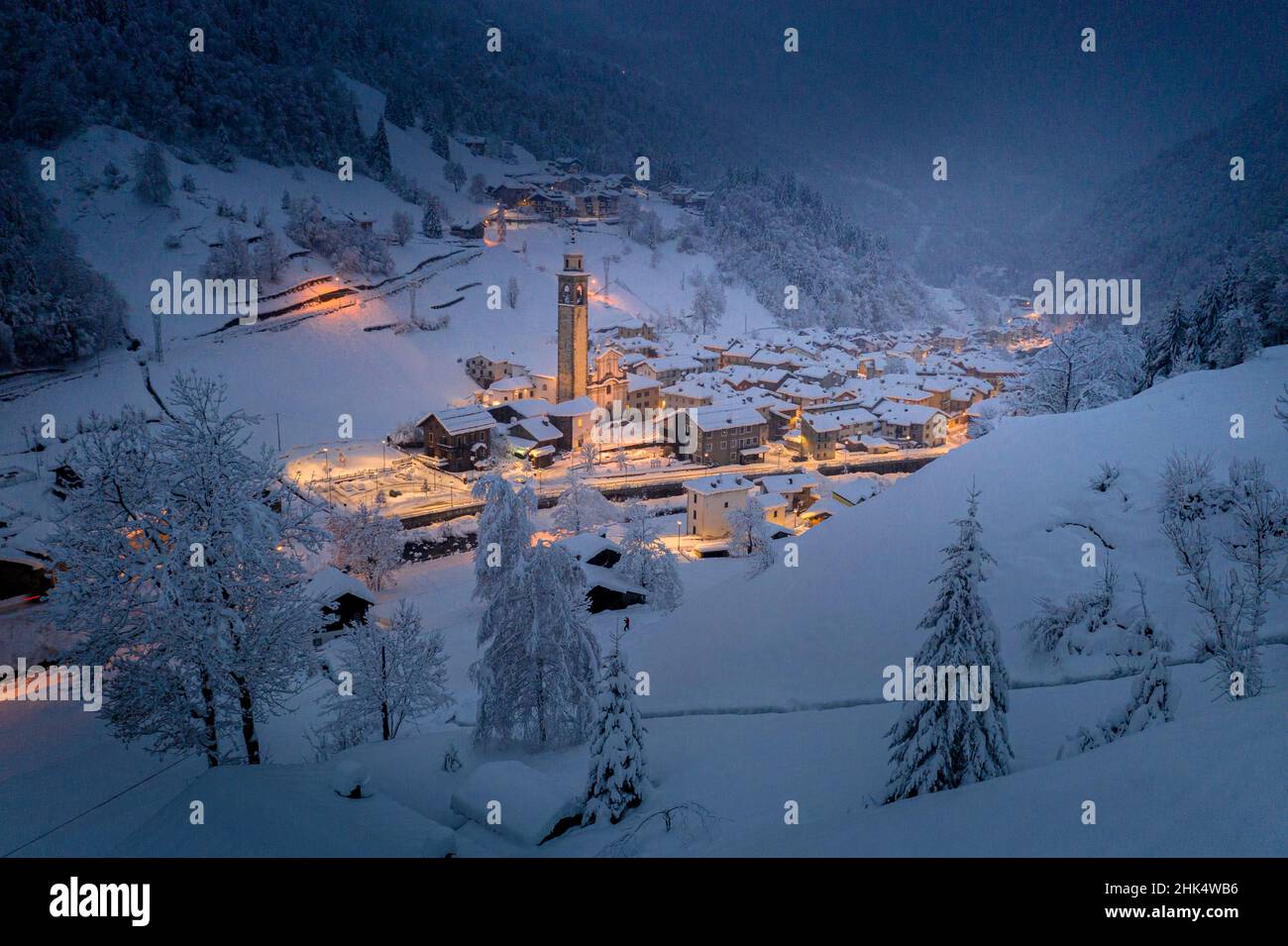 Winter dusk over the illuminated village in deep snow, Gerola Alta ...