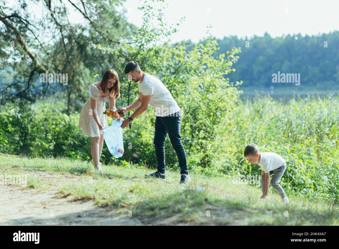 family volunteer cleans garbage in nature. Father and mother, parents ...