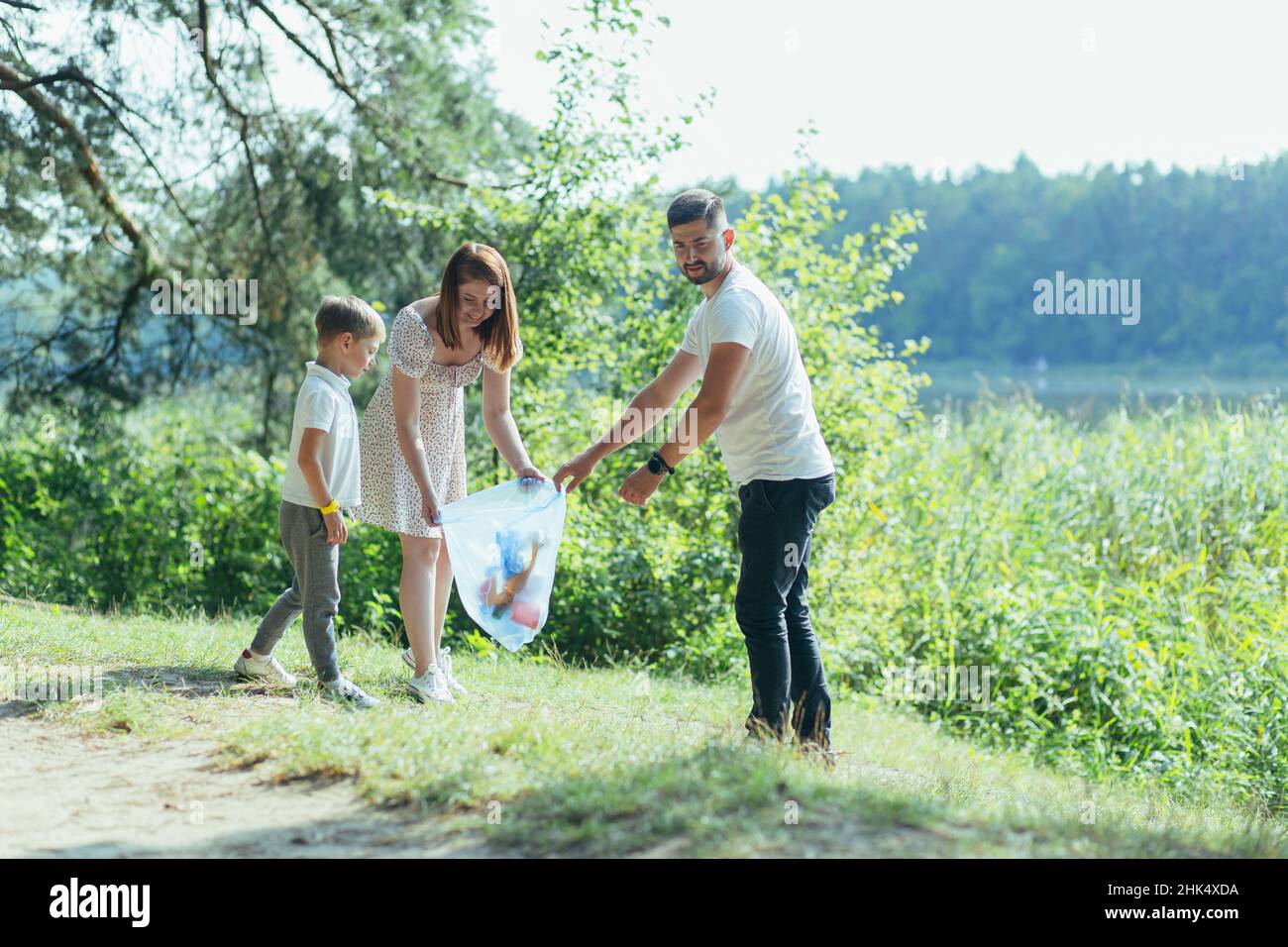 family volunteer cleans garbage in nature. Father and mother, parents ...