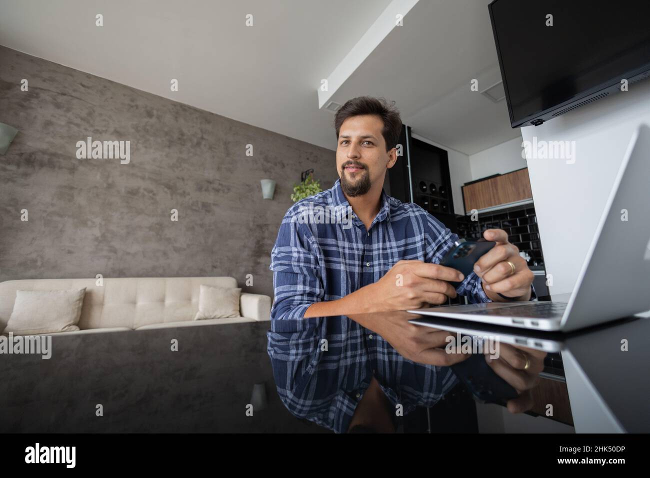 Young white man working at home with laptop on desk. Home office ...