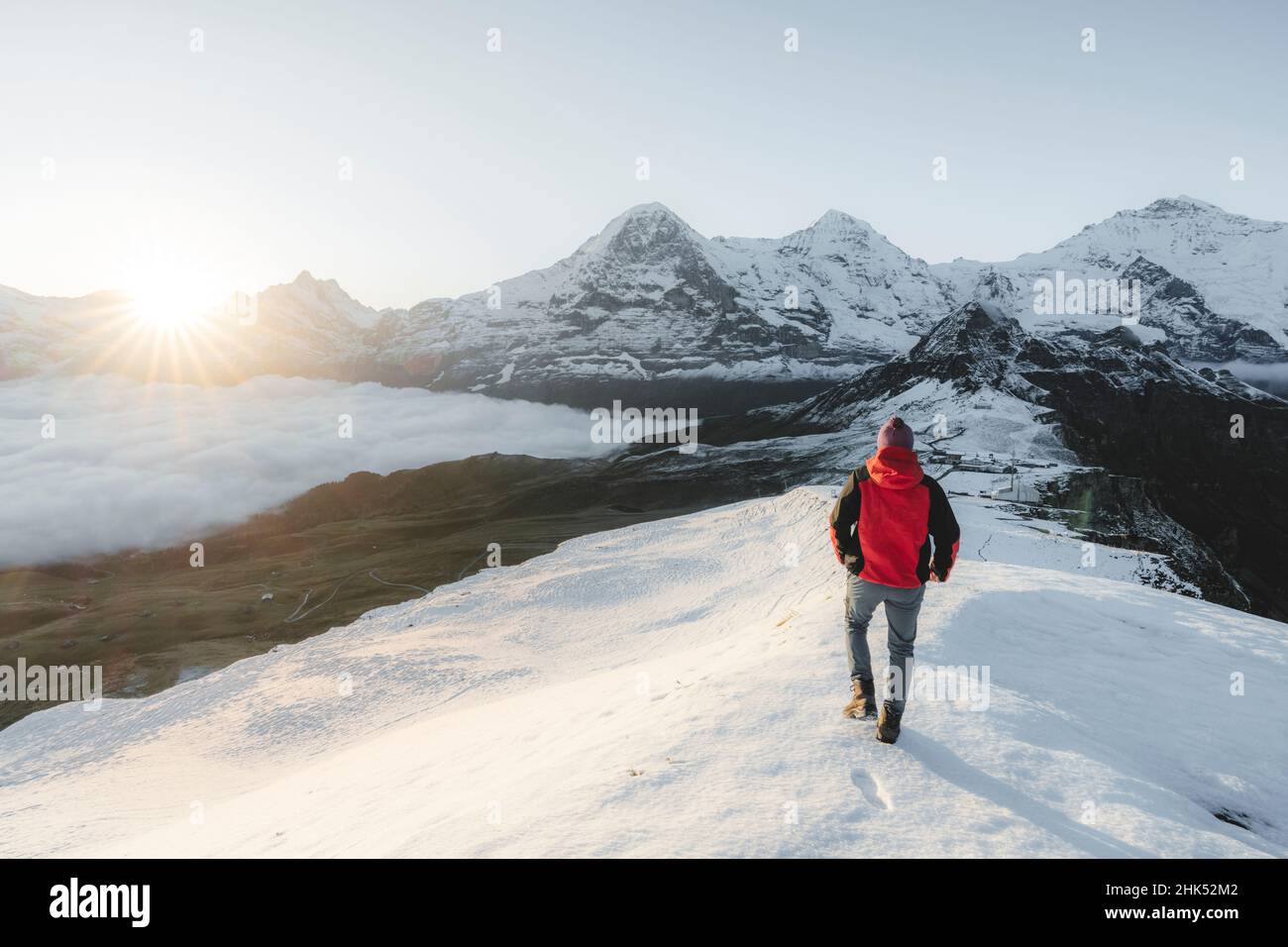 Man in the snow admiring Eiger, Monch and Jungfrau peaks at dawn ...