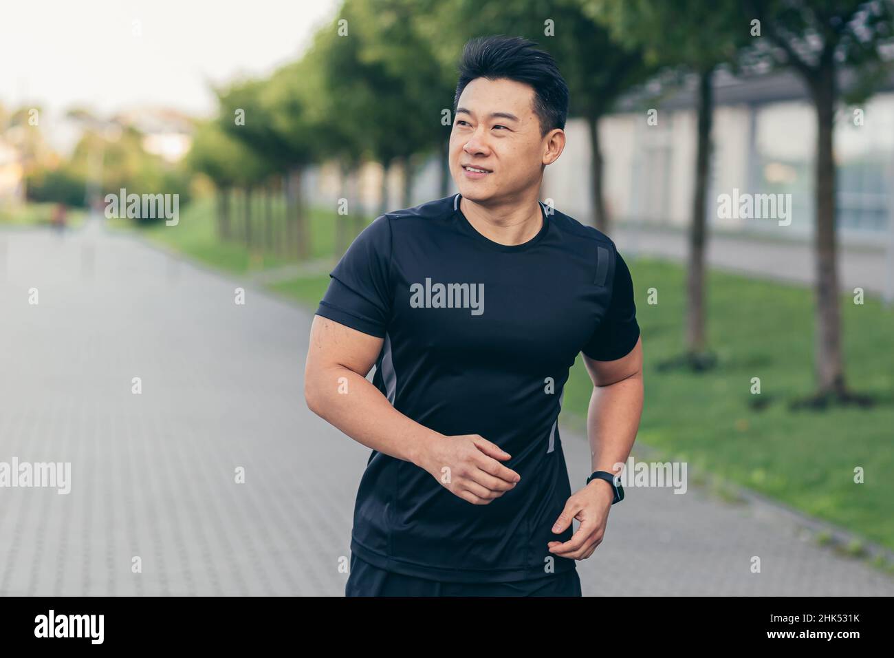 Male asian athlete running in the park in a backpack before work ...