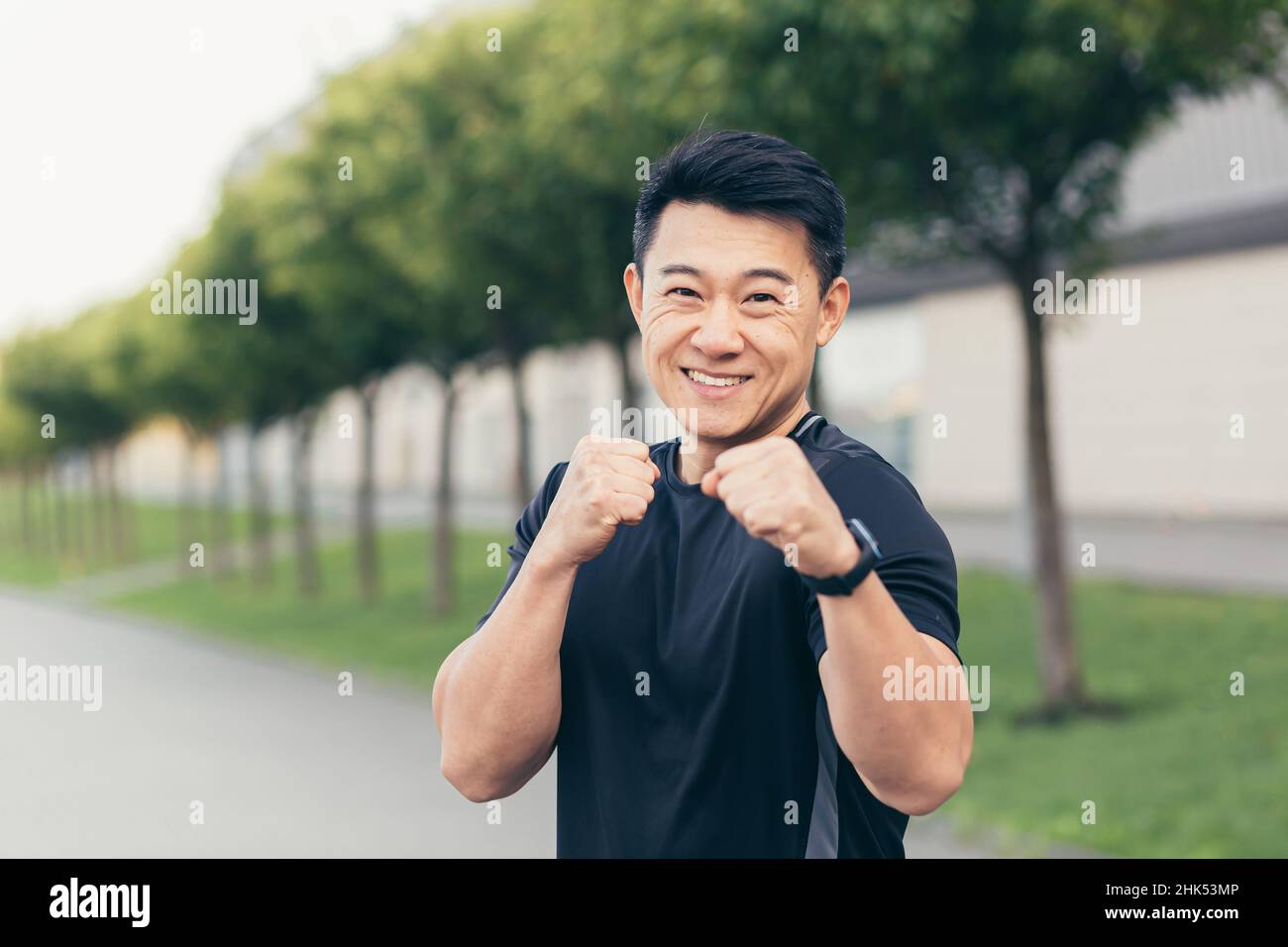 Male asian athlete demonstrates boxing rack during morning jogging and ...