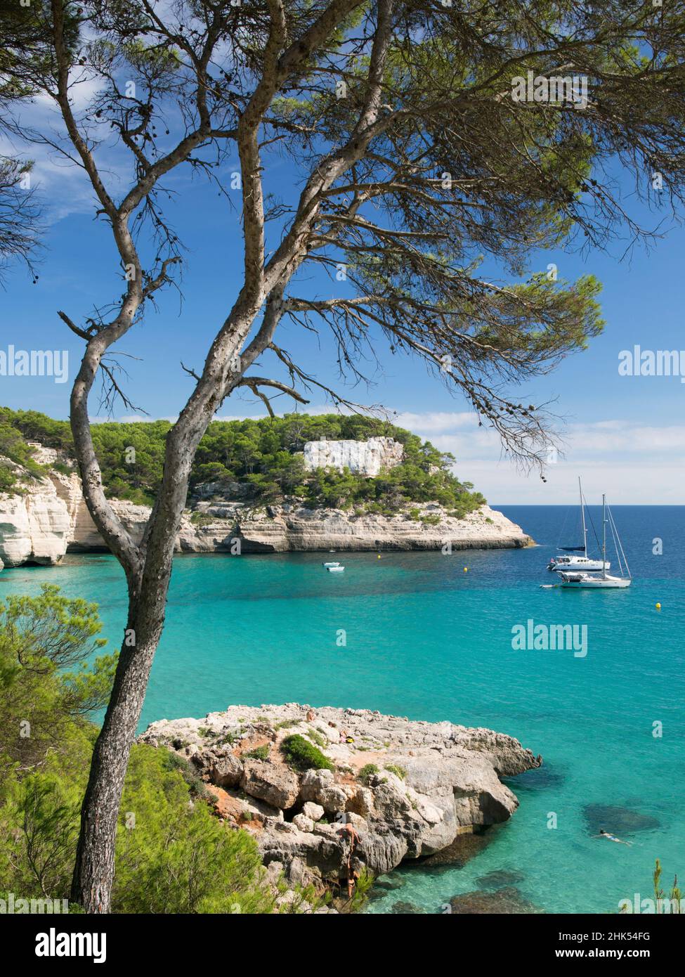 View over the turquoise waters of Cala Mitjana to pine-clad limestone ...