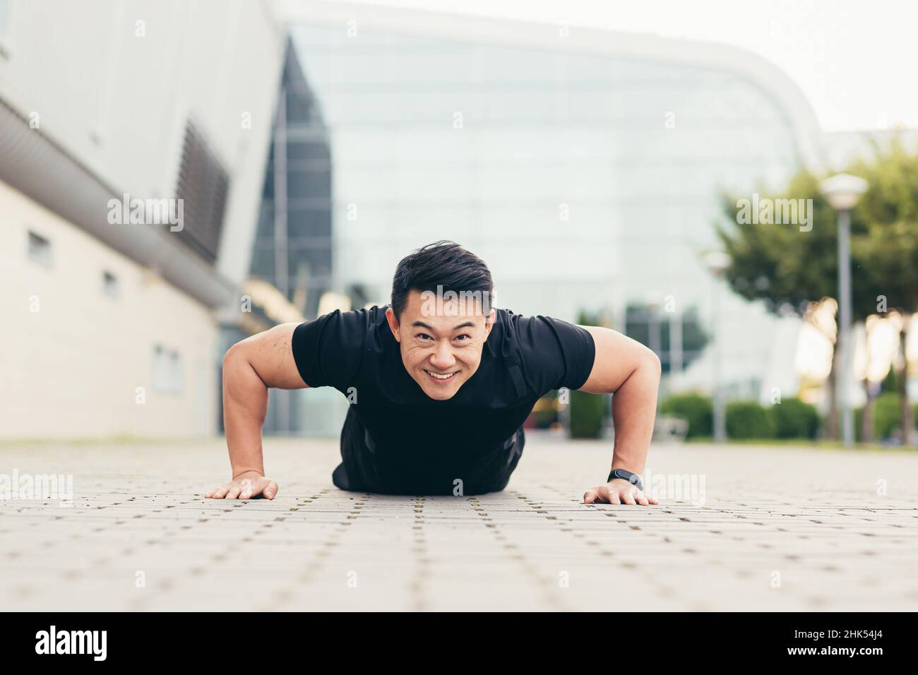 Male asian athlete doing fitness in the morning near the stadium pushes ...