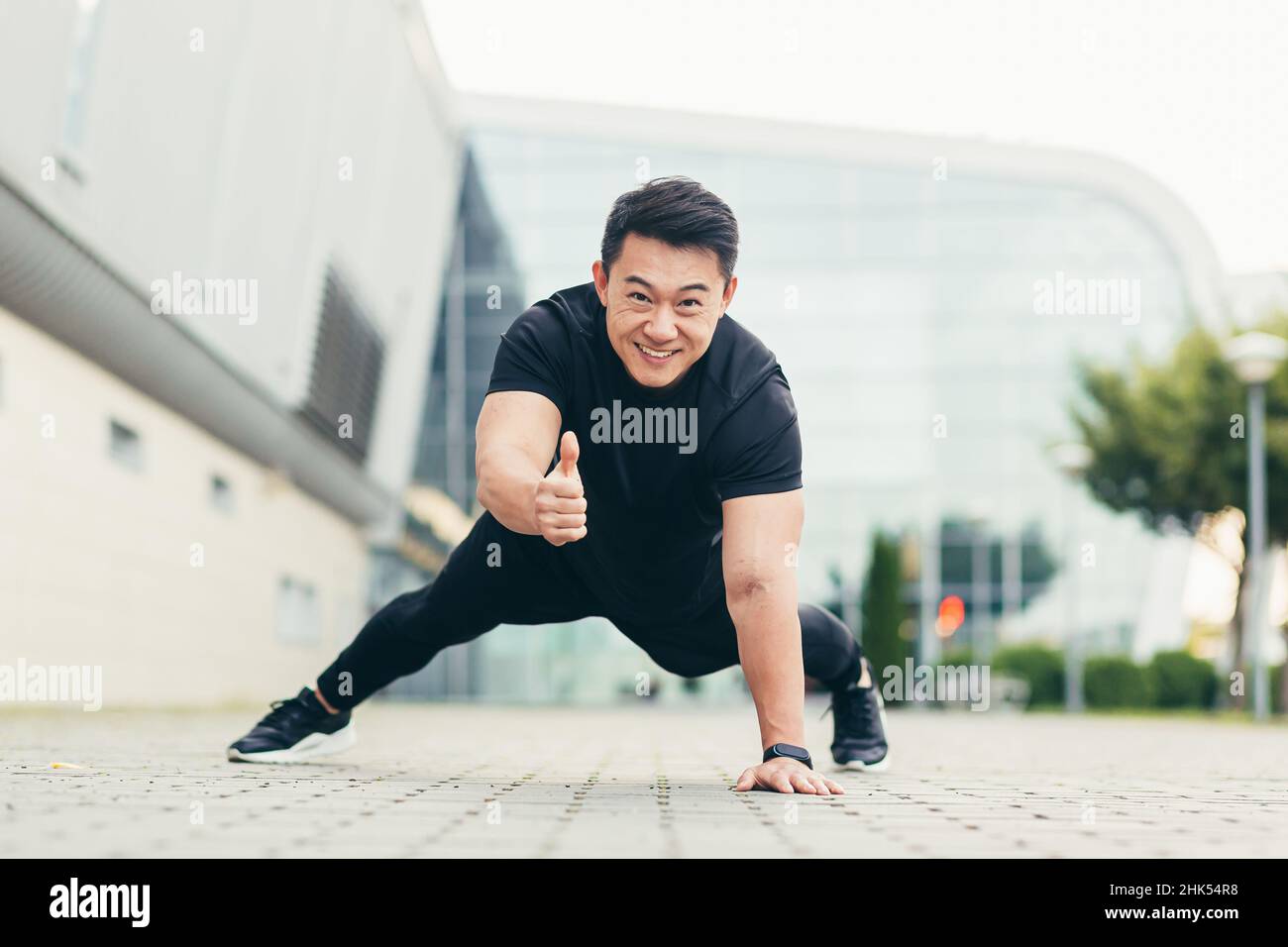 asian athlete performs sport pushing off the ground looks at the camera ...