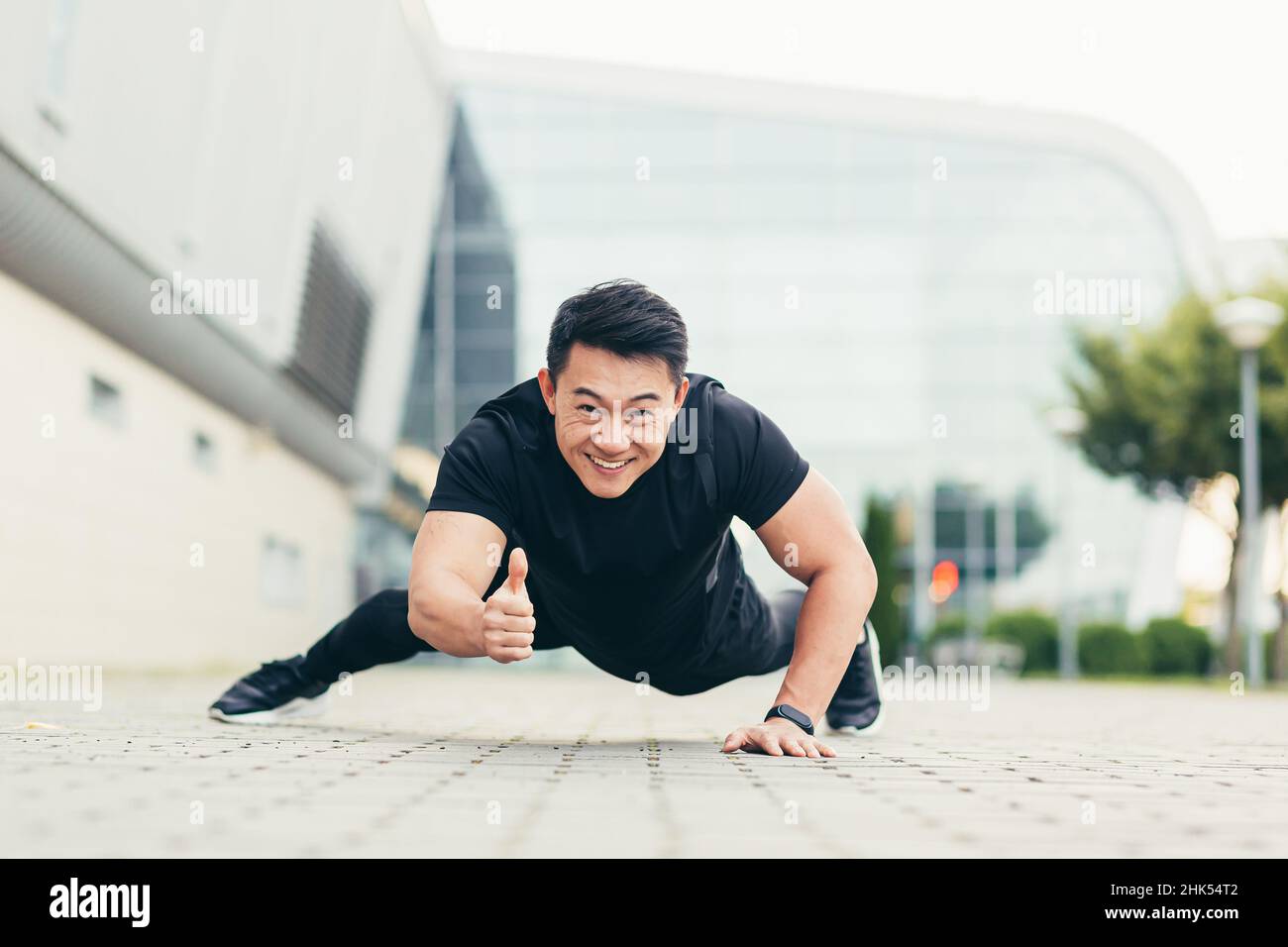 asian athlete performs sport pushing off the ground looks at the camera ...