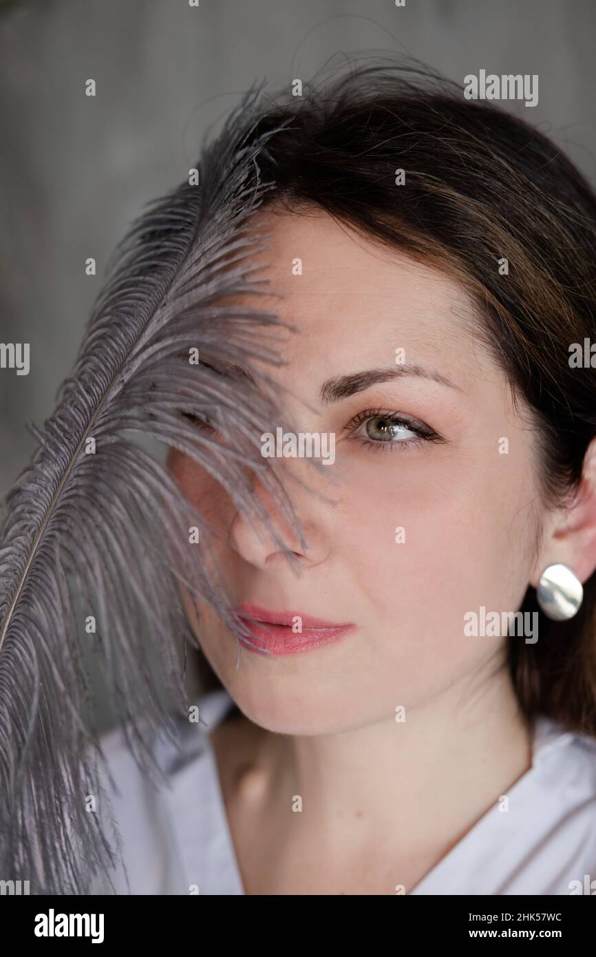 portrait of brunette woman girl holding big grey soft fluffy feather ...