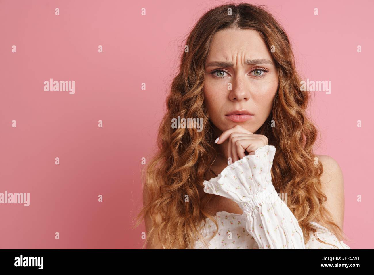 Young ginger woman in dress frowning and looking at camera isolated ...