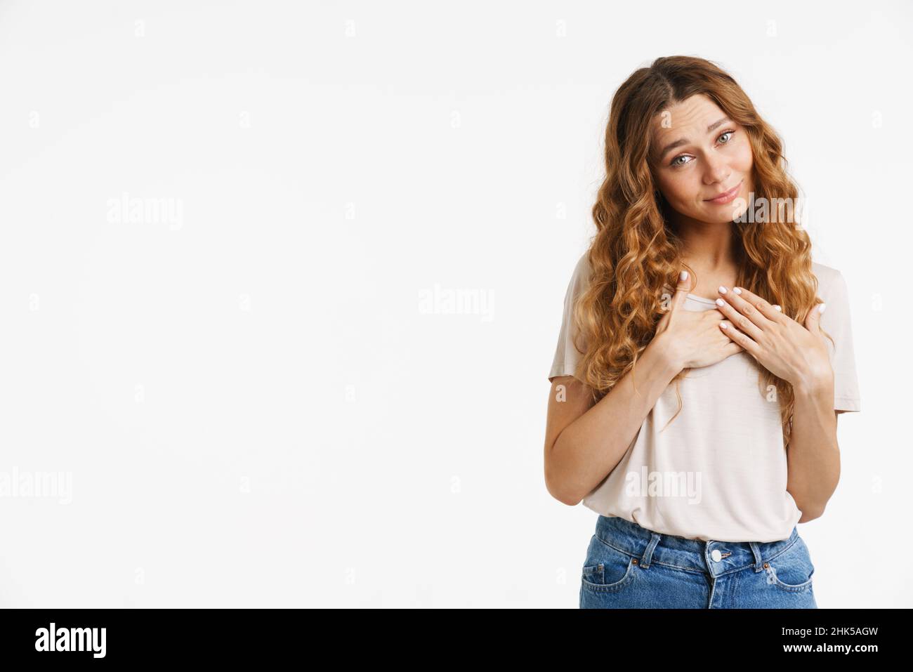 Young ginger woman smiling and holding hands on her chest isolated over ...