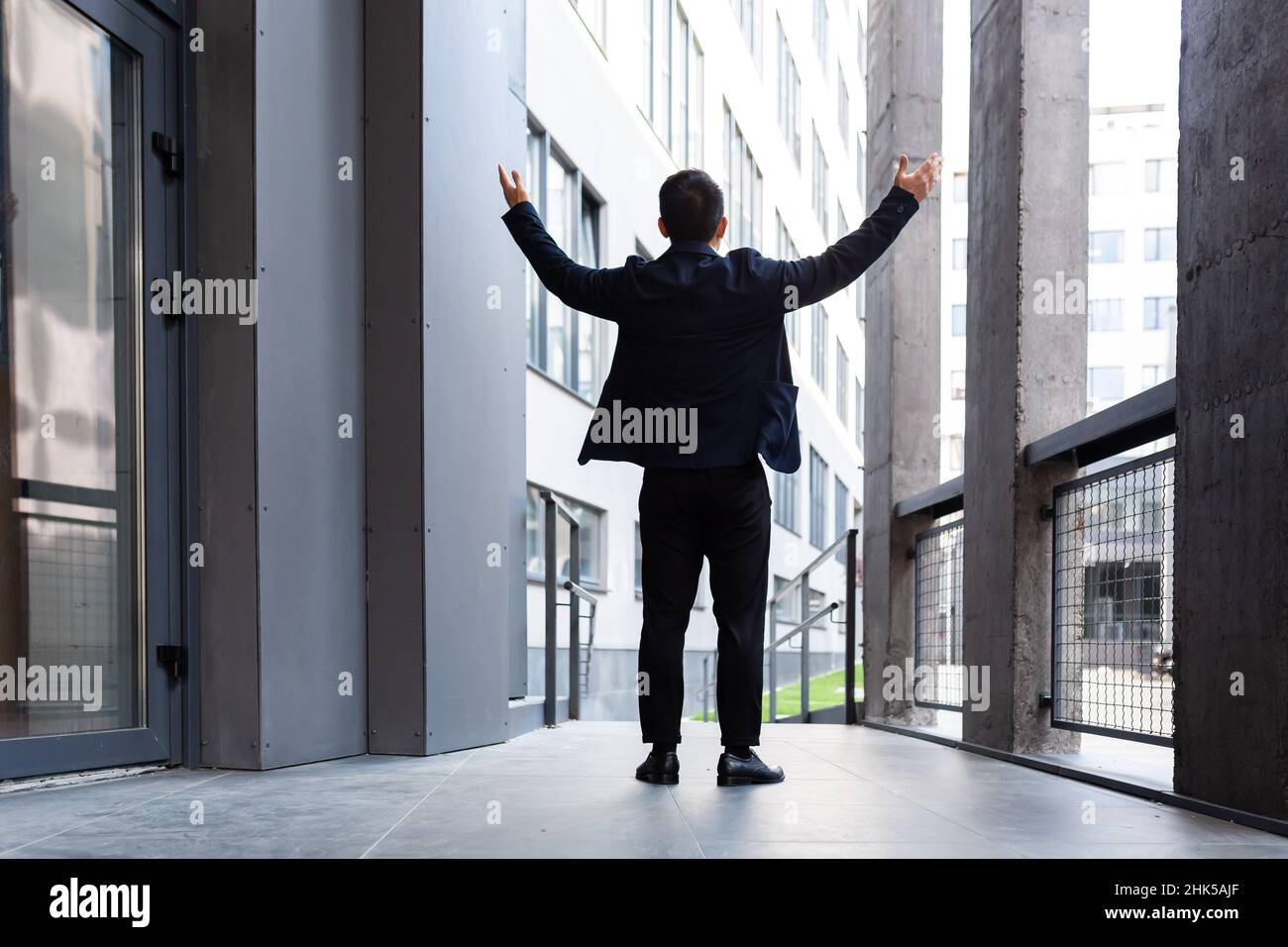 Successful businessman raises his hands up a sign of victory and ...