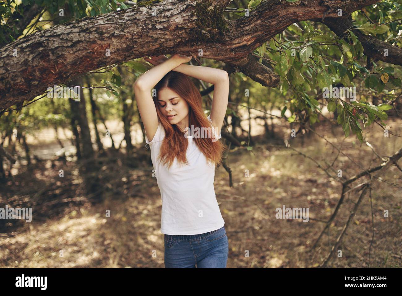 woman touching tree branch with hands on nature in garden summer ...