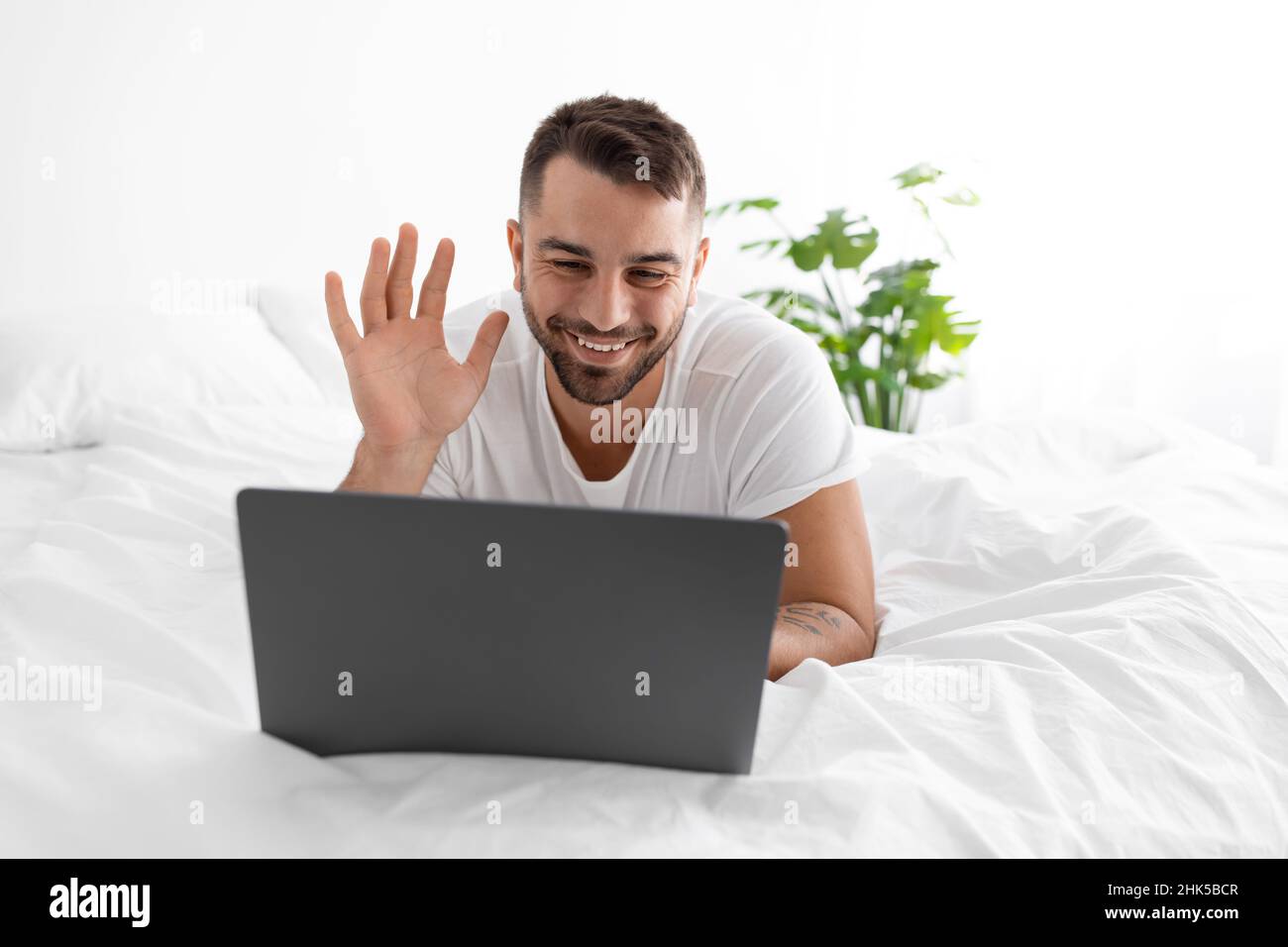 Smiling handsome millennial muscular caucasian guy typing on computer ...