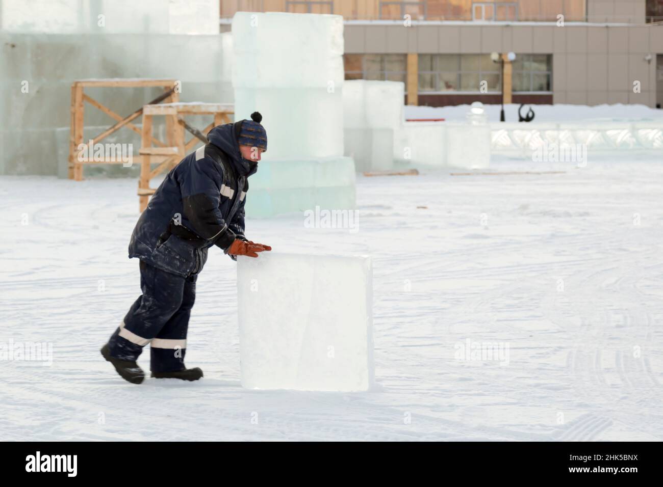 A worker drags an ice block with his hands along the assembly site of ...