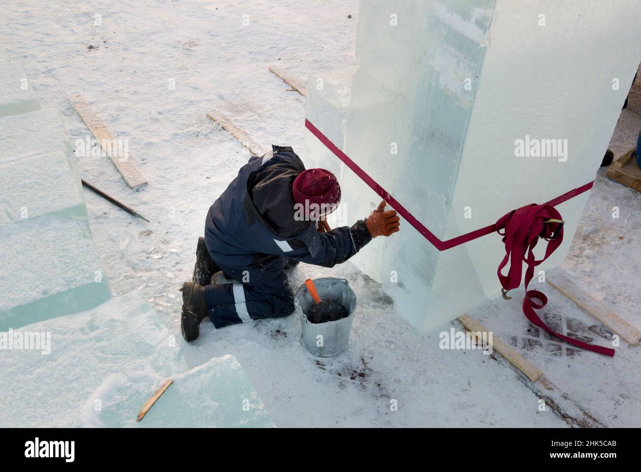 The installer at the construction site of the ice town covers the ...