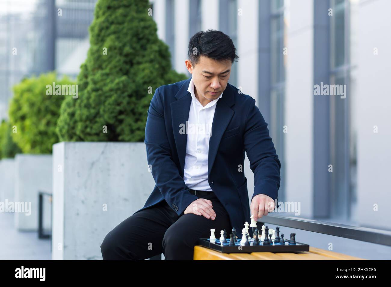 Serious asian man playing chess outside, businessman thinking playing ...