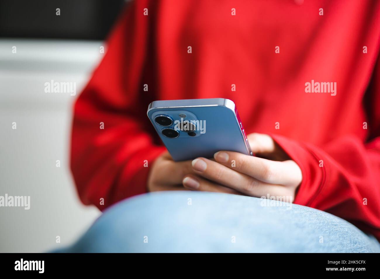 Young girl using mobile phone with triple camera. White woman typing ...