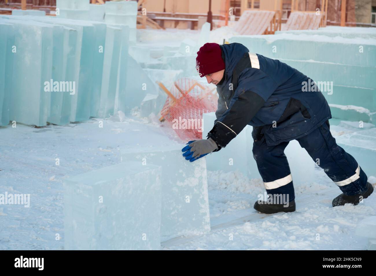 A worker drags an ice block with his hands along the assembly site of ...