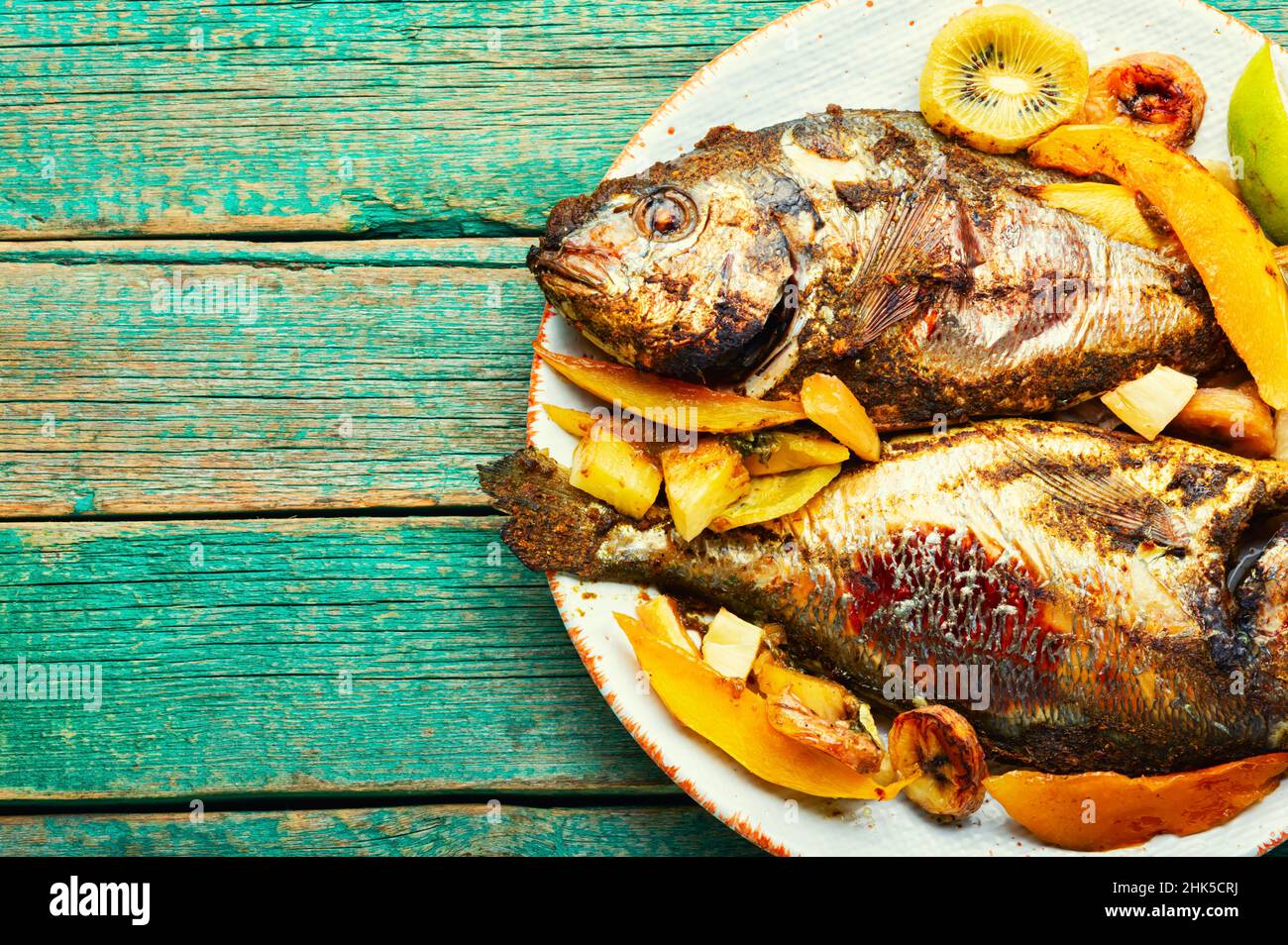 Delicious fried fish dorada with fruits and spices. Space for text ...