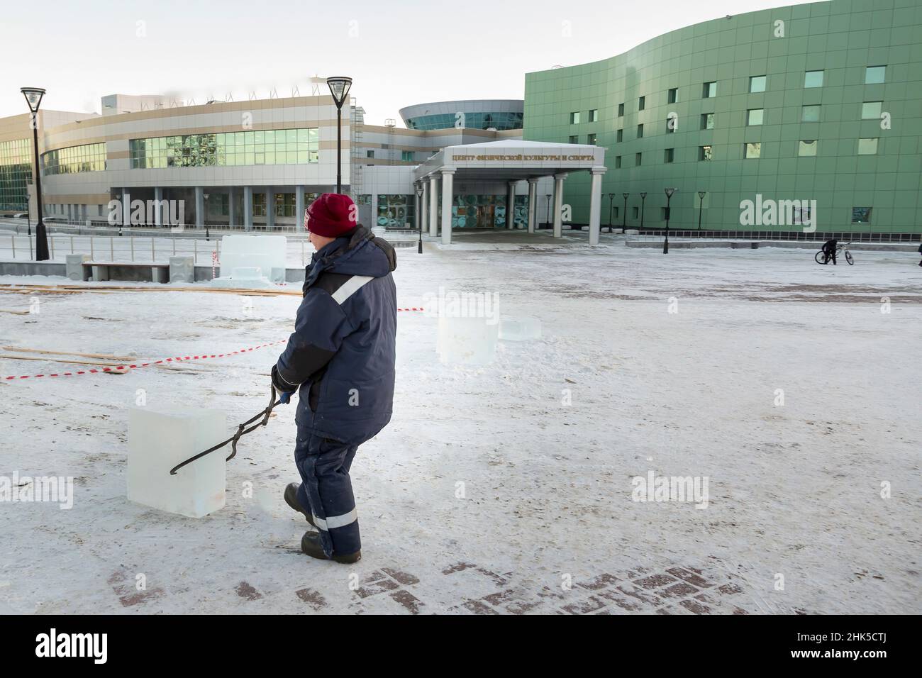 The worker pulls the ice block around the ice camp assembly site with ...