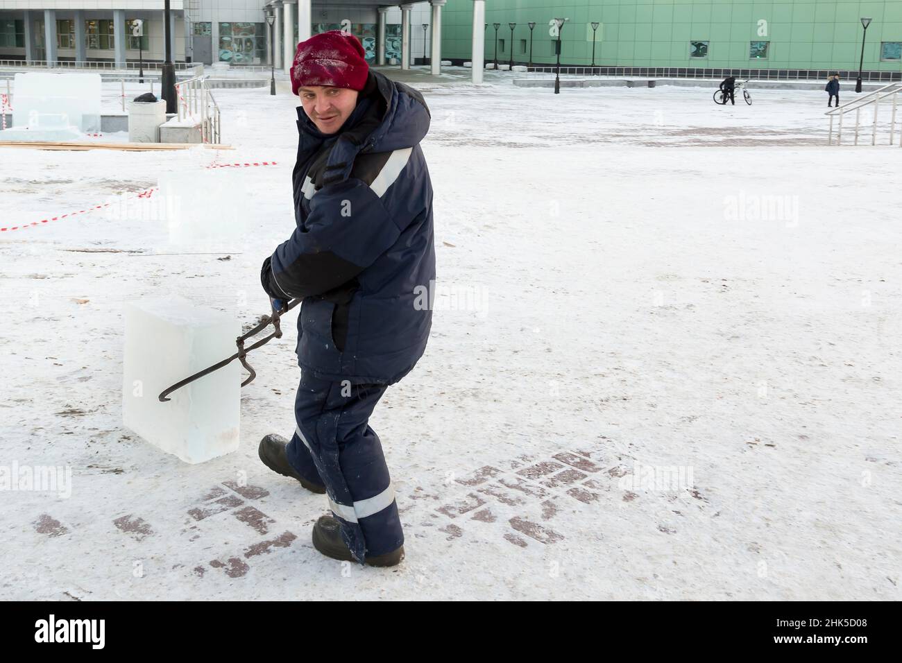 The worker pulls the ice block around the ice camp assembly site with ...