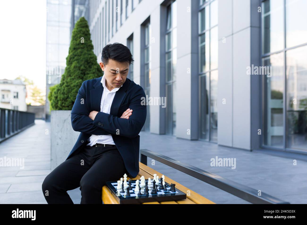 Serious asian man playing chess outside, businessman thinking playing ...