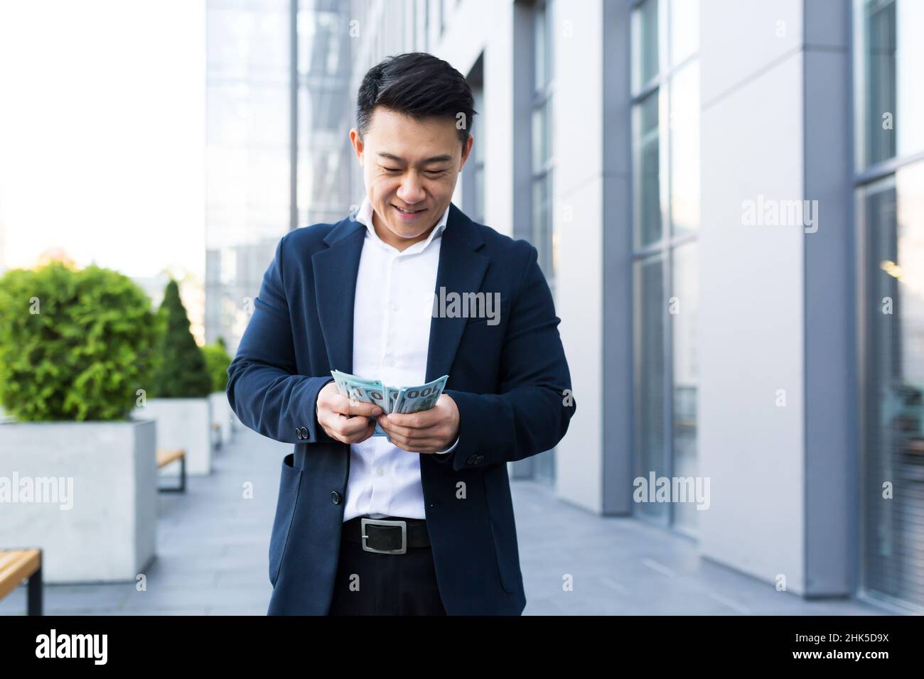 Asian man counts money near the office, happy businessman got a lot of ...