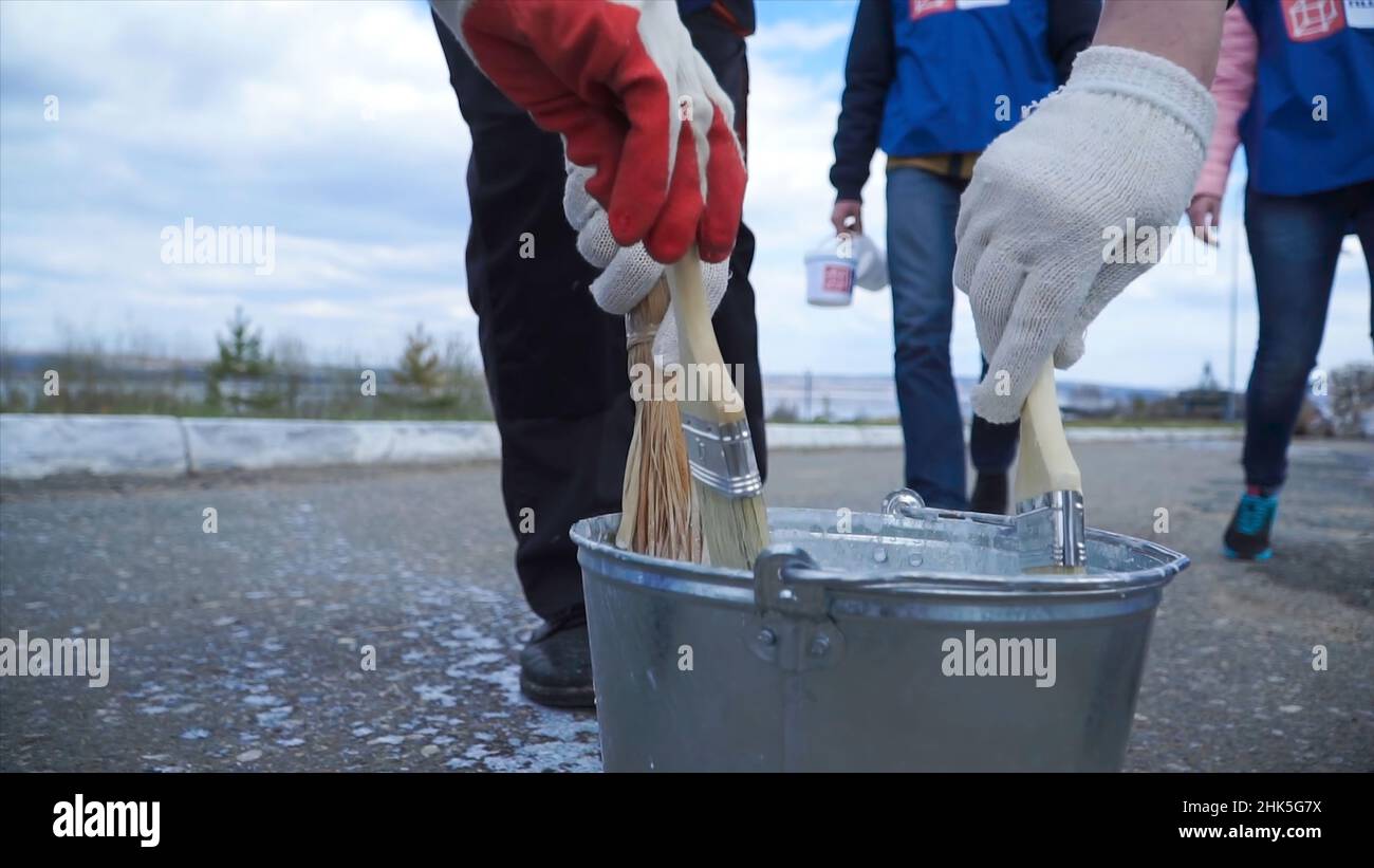 Hands dipping paint into a full paint cup. Clip. Closeup of a worker ...