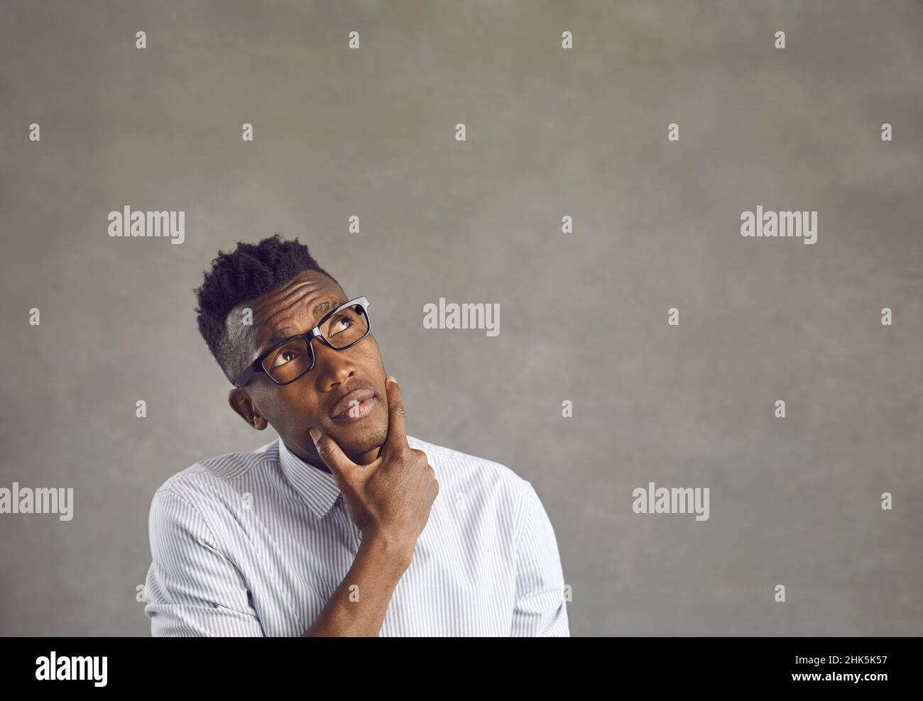 Puzzled confused dark-skinned man looks up and scratches his chin ... Puzzled confused dark-skinned man looks up and scratches his chin ...