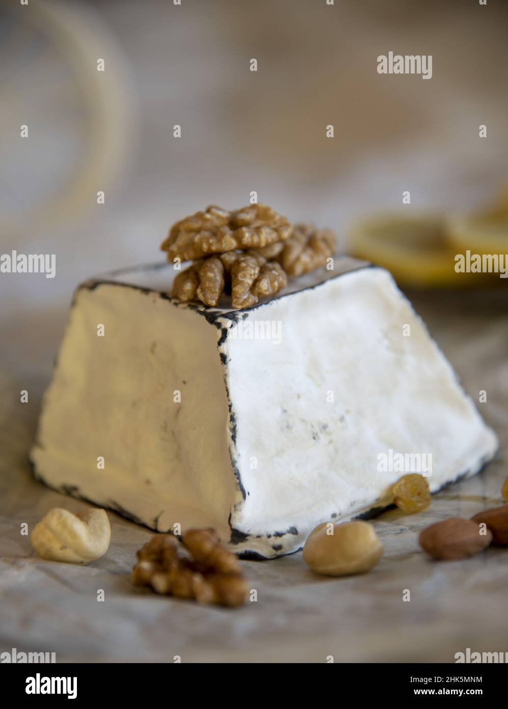 Cheese in white mold with black charcoal edges, nuts and raisins, on ...