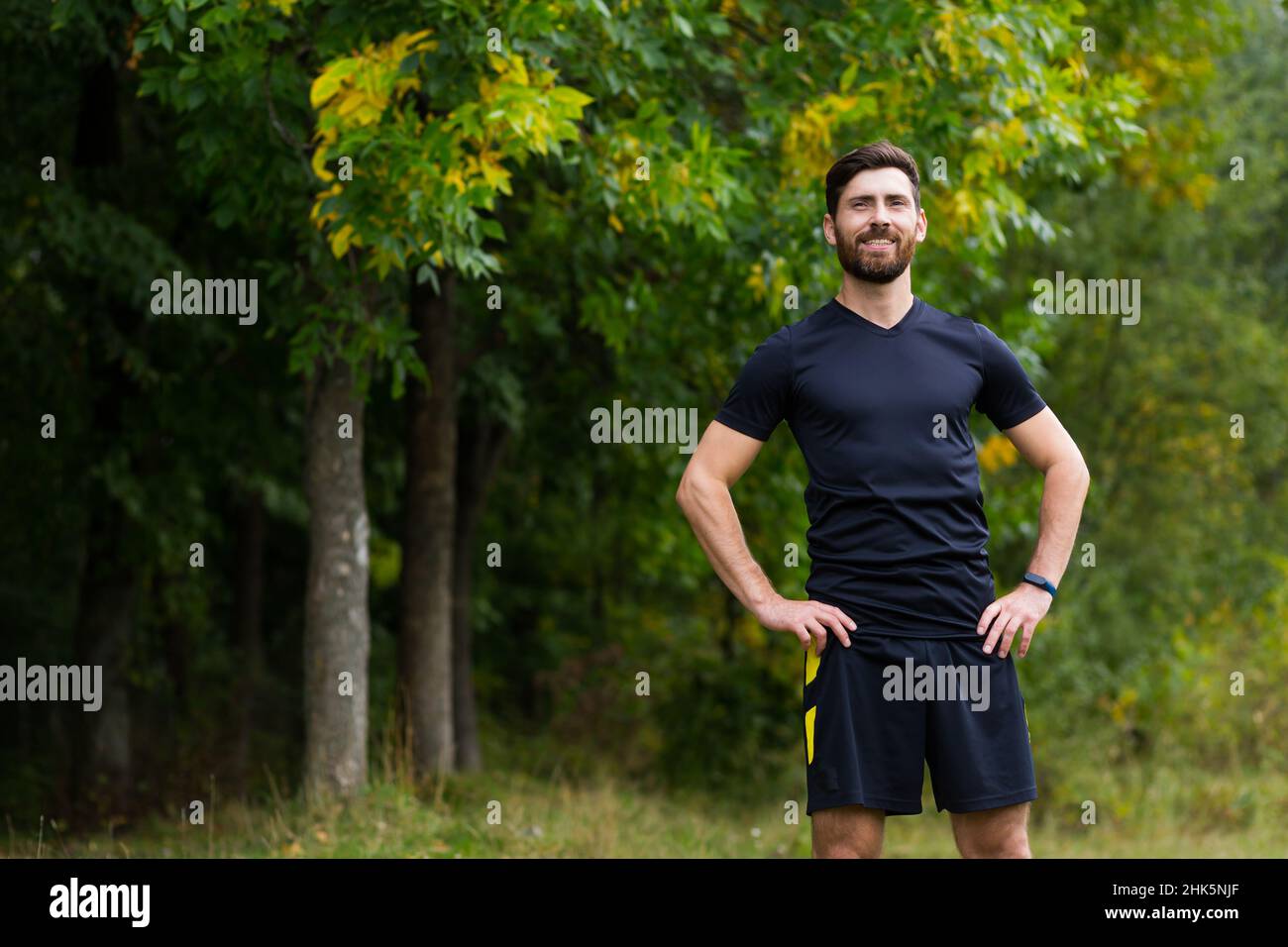 Close up portrait young happy bearded man standing in nature between ...