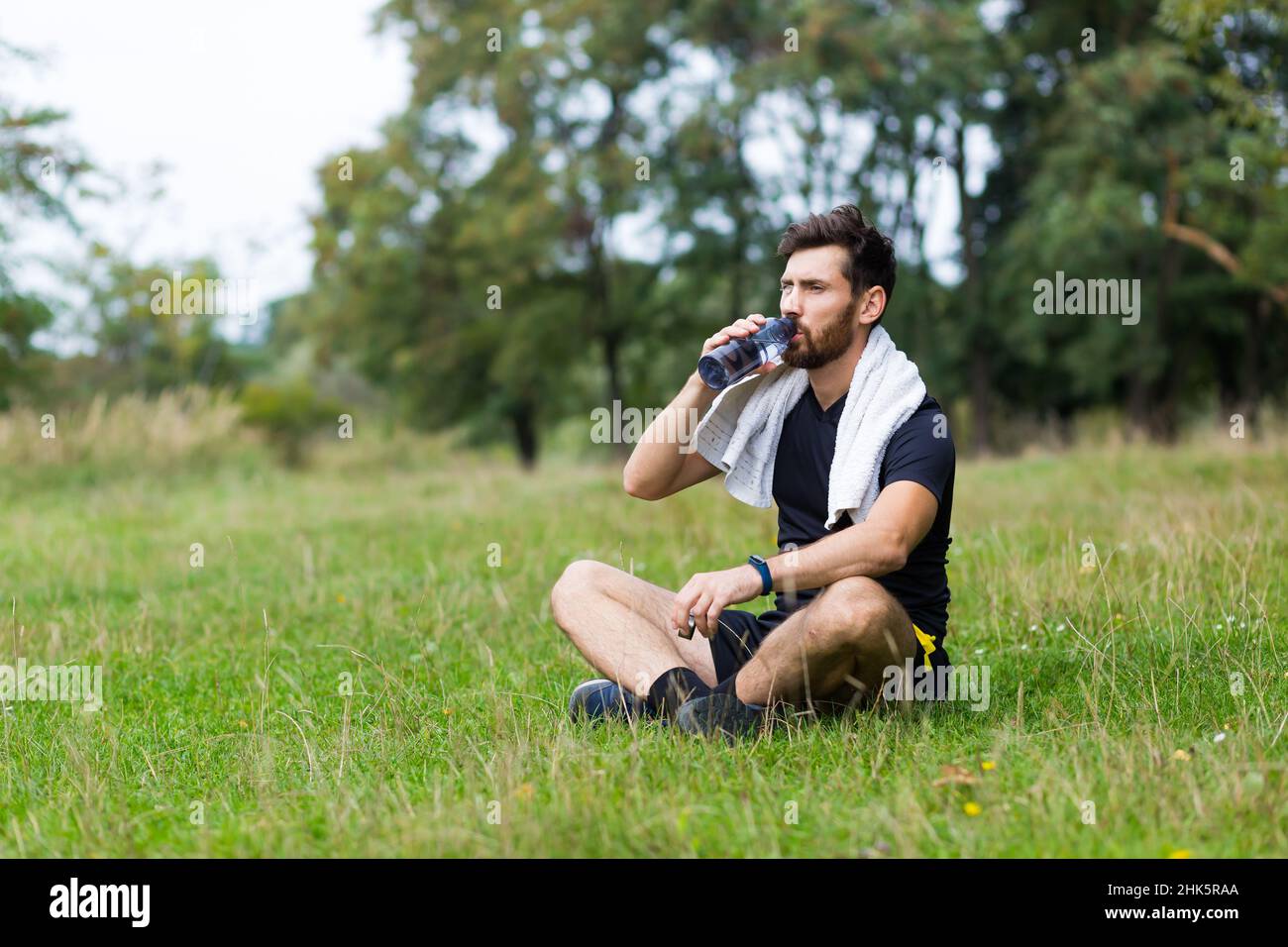 Tired exhausted dehydrated Athlete man runner drinking water bottle ...