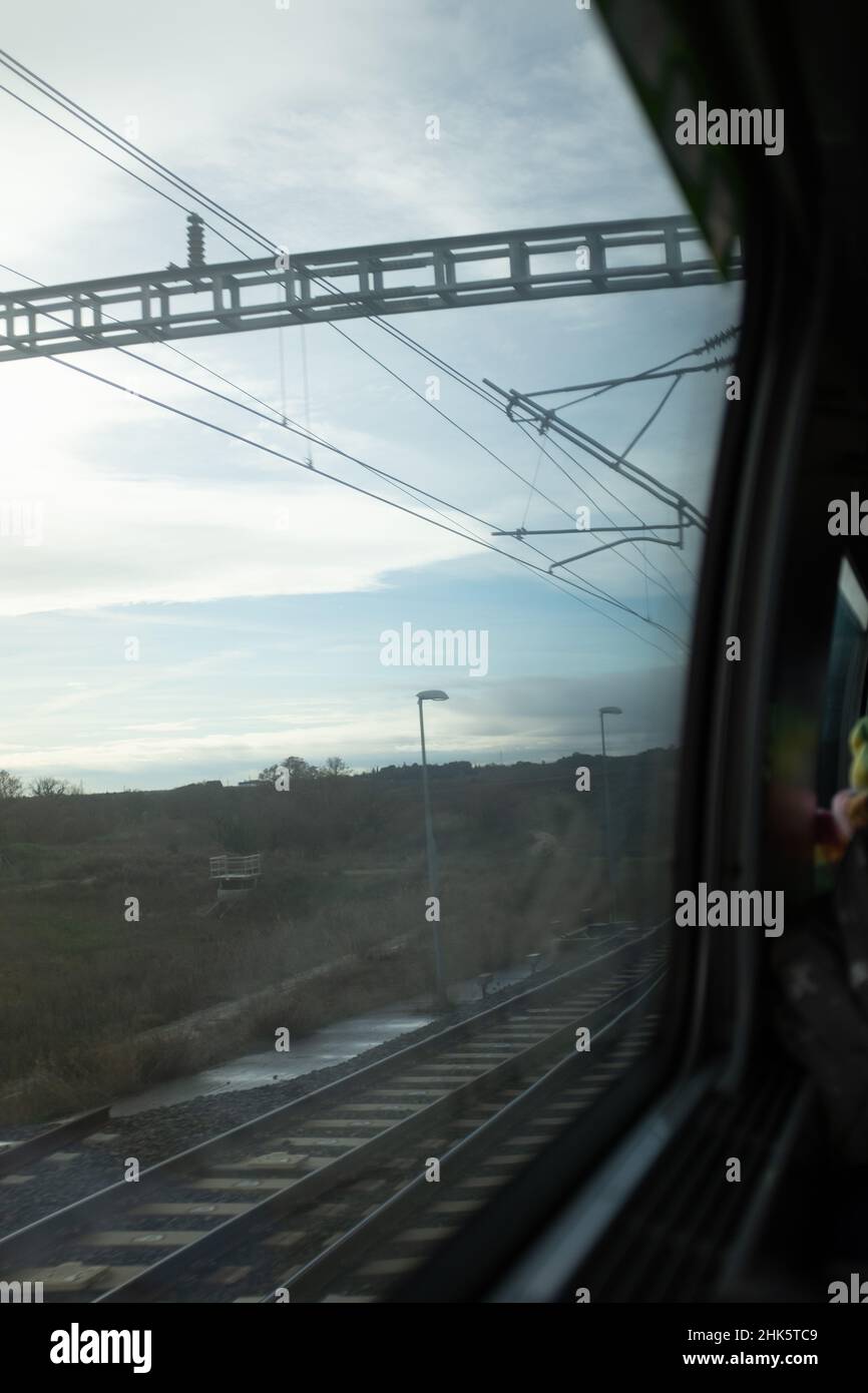 Window scene on a train in movement crossing railways and cloudy sky ...