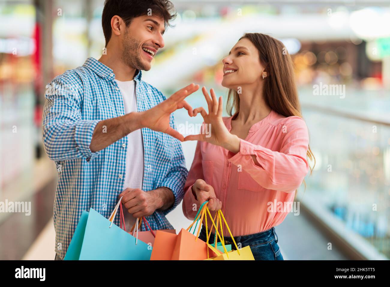 Couple Shopping Making Fingers Heart Holding Shopper Bags In Mall Stock ...