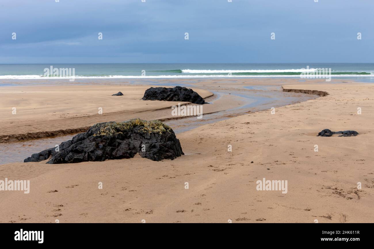 Layers of an incoming tide and rocky beach on the Downhill Beach in the ...