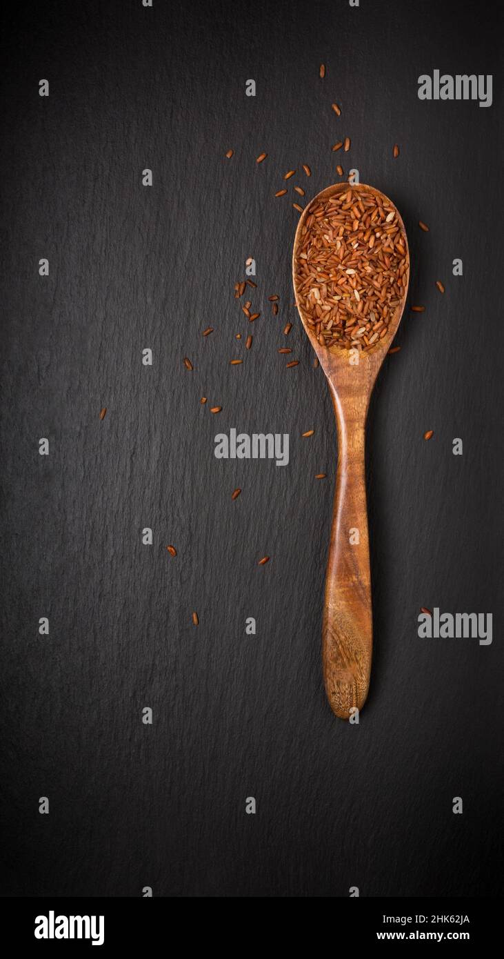whole grain dark brown rice in a wooden spoon, also called purple rice ...